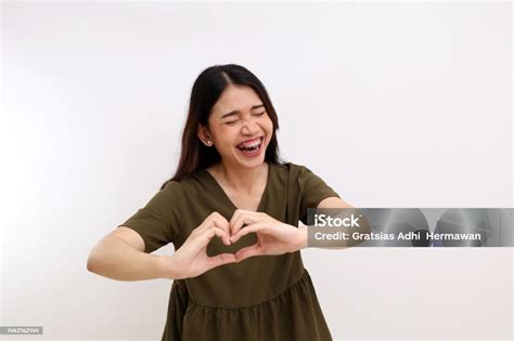 Young Asian Woman Laughs Out Loud While Showing Love Shape Hand Gesture