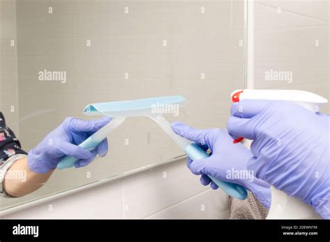 Closeup Female Hands Sprinkle Cleaning Agent On The Bathroom Mirror And