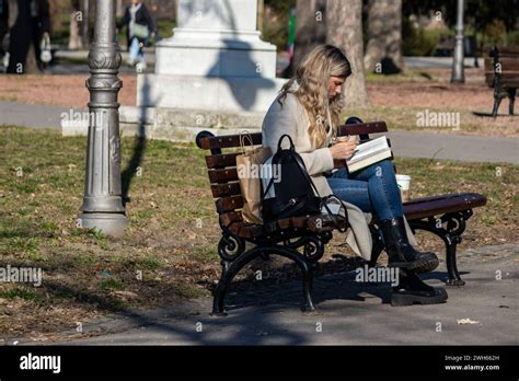Young Woman Sitting In Public Park Bench On Sunny Day Enjoying Nice