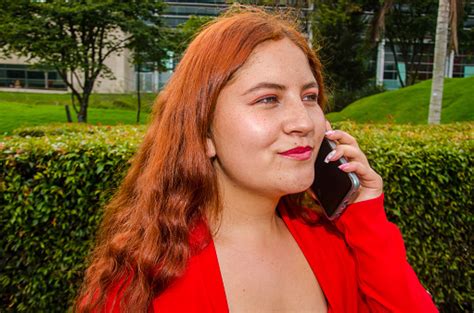 빨간 머리와 파란 눈을 가진 아름 다운 여자가 배경에 현대적인 건물과 함께 공공 공원에서 야외에서 스마트 폰을 사용 25 29세에 대한 스톡 사진 및 기타 이미지 Istock