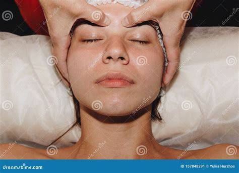 Spa Specialist Is Doing Facial Massage To A Young Girl In A Medical Cap