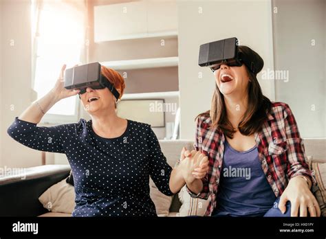 Excited Adult Daughter With Mother At Home Wearing Vr Glasses Stock
