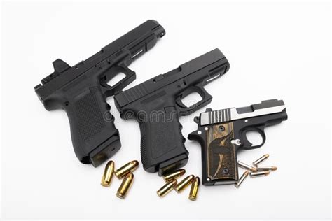 Different Size Of Semi Automatic Hand Gun And Bullets On White
