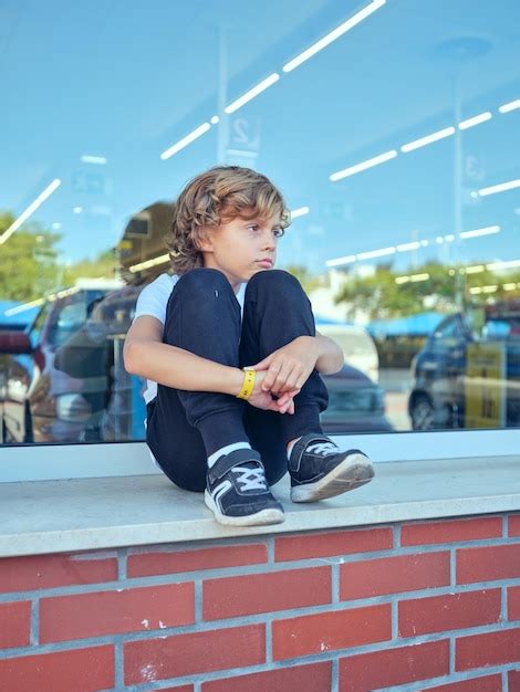Premium Photo Sad Boy Sitting On Windowsill In City