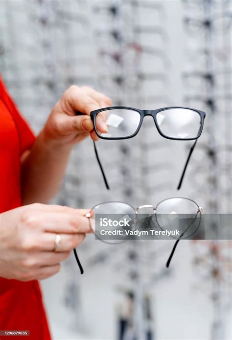 Womans Hands Holding Two Pairs Of Glasses In Modern Frames Choosing
