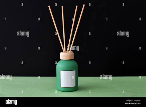 Reed Diffuser Oil Bottle With Blank White Label On A Green Base Isolated Against A Black