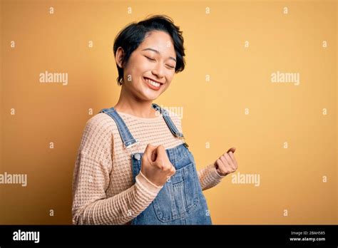 Young Beautiful Asian Girl Wearing Casual Denim Overalls Over Isolated