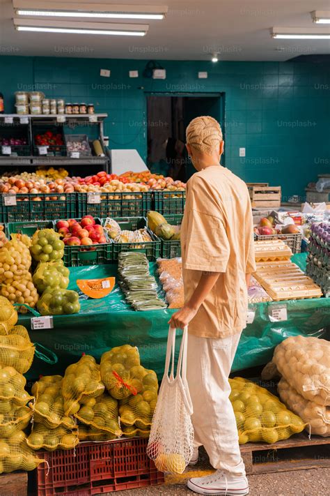 A Man Standing In Front Of A Fruit Stand Photo Farmers Market Image
