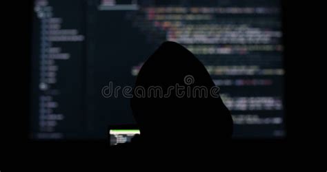 hacker in hood working in dark abstract room programming code on a