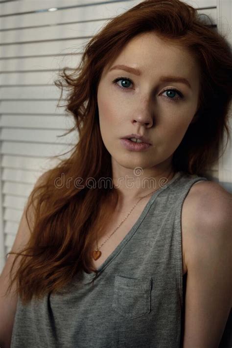 Una Hermosa Pelirroja Con Su Pelo Y Pecas En Una Camiseta Gris Está Mirando a La Cámara