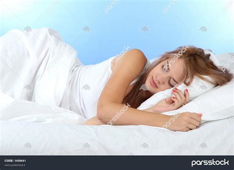 زن زیبا و جوان زیبا که روی تختخواب روی زمینه آبی خوابیده است 1458441