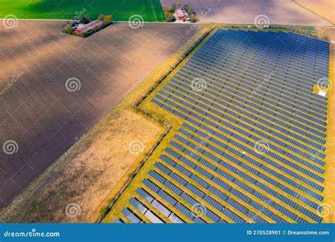 A Solar Park With Many Solar Panels Next To Fields And A Farm From