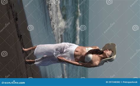 Barefoot Woman Dressed In Bikini Top Capri Pants And Straw Hat Walking