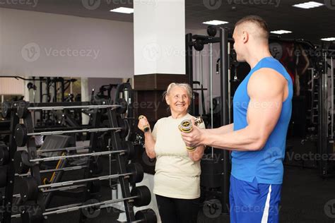 An Old Woman And A Young Male Coach Do Exercises In Gym They Shake