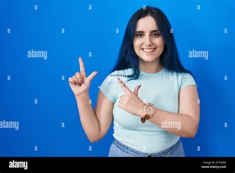 Young Modern Girl With Blue Hair Standing Over Blue Background Smiling
