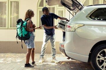 Smiling Young Couple Prepares For A Vacation Loading The Car Trunk