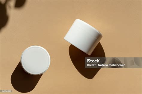 그림자가있는 베이지 색 배경에 두 개의 흰색 항아리에 크림을 바르십시오 햇빛의 광선에 화장품을위한 깨끗한 패키지의 모형 클로즈업 플랫 레이 복사 공간 생활필수품에 대한 스톡