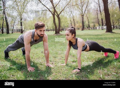 Two People Are Staying In A Plank Position On Grass In Park They Are
