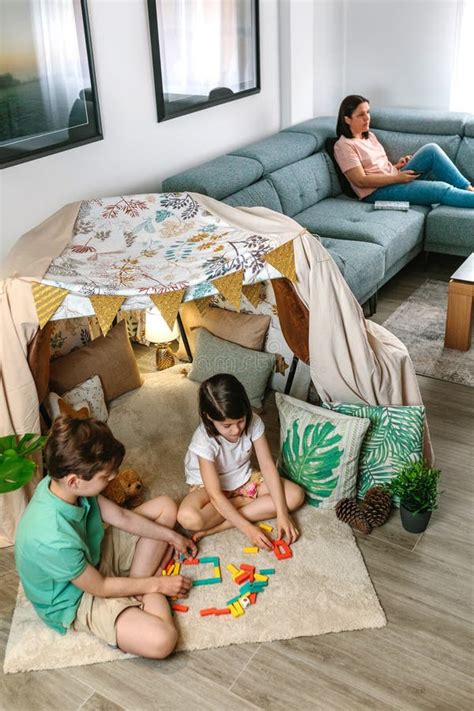 Ni Os Jugando Con Un Juego De Piezas Apiladas Mientras Su Madre Se Relaja Usando El Control