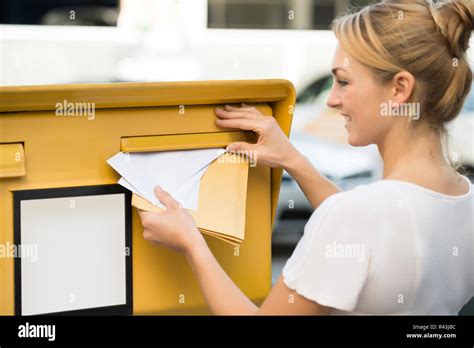 Woman Inserting Letter In Mailbox Stock Photo Alamy