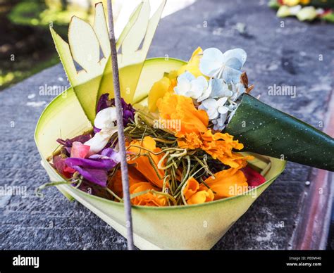 Balinese Canang Sari Offering With Orange Flowers And An Incense Stick