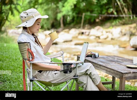 Relaxed Young Asian Female Camper Using Laptop Computer Sipping Coffee