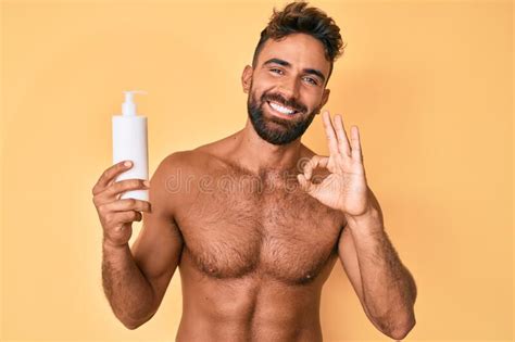 Young Hispanic Man Standing Shirtless Holding Sunscreen Lotion Doing Ok