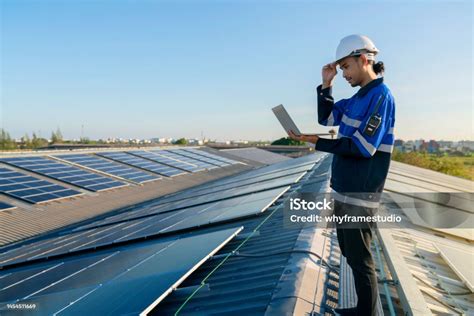 노트북 및 태블릿 유지 보수 검사를 갖춘 전문 기술자 전문 엔지니어가 햇빛 아래 공장 옥상에 태양 광 지붕 패널을 설치합니다 태블릿을 들고 엔지니어는 태양 지붕을 확인합니다