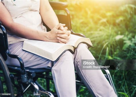 Foto De Mulher Paralisada Está Rezando Sobre Bíblia Aberta Em Uma Cadeira De Rodas Com Fundo De