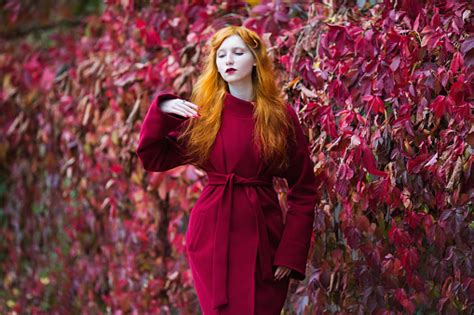 밝은을 바탕에 빨간 코트에 붉은 스트레이트 머리를 가진 여자 창백한 피부와 파란 눈과 손가락 및 빨간 손톱에 반지와 함께 밝은 특이 한 외관을 가진 빨간 머리 소녀 스트리트