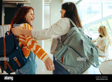 Two Happy Classmates Share A Friendly Greeting In A Bright School