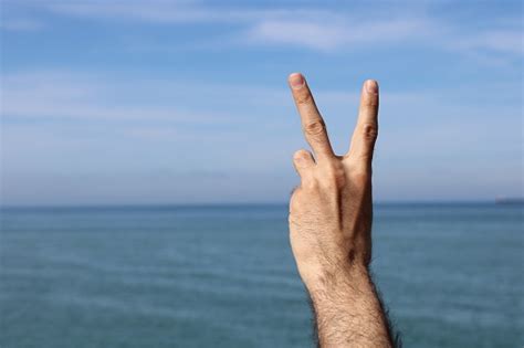 Hand Doing Showing Number Two Gesture Symbol On Blue Summer Sky Nature