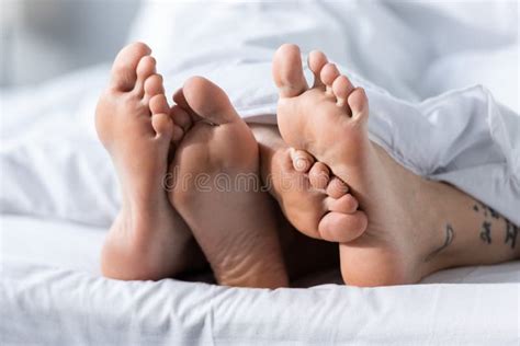 Two Lesbians Lying Under White Blanket And Looking At Each Other In