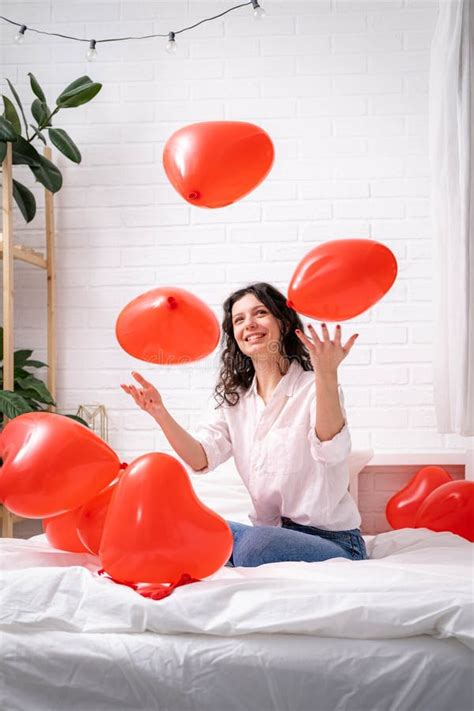 Brunette European Girl Rejoices Playing On Bed With Red Heart Shape Balloons Morning Love
