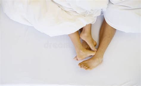 Four Legs And Feet Close Up Top View From Above Of Loving Couple