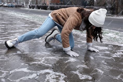 Premium Photo Young Woman Trying To Stand Up After Falling On Slippery Icy Pavement Outdoors