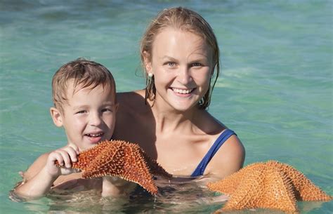 Premium Photo Portrait Of Happy Mother And Son With Starfish In Sea