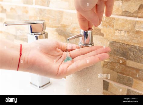 Woman Putting Liquid Soap In Palm From Container As Preparing To Wash