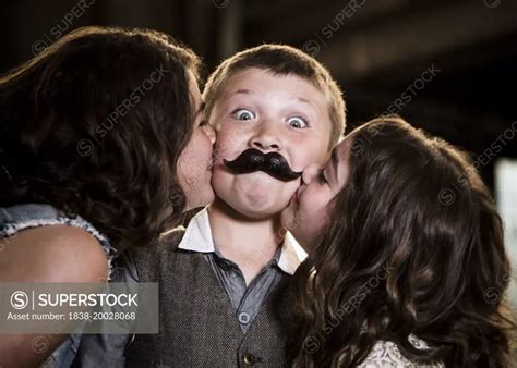 Two Girls Kissing Boy With Wax Lips In Abandoned Warehouse Superstock