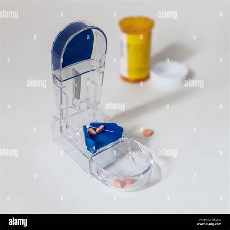 On A White Surface We See A Pill Splitter Halved Doses And A