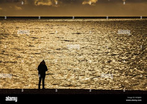 Seaton Devon 15th Jan 2019 A Woman Looks Out To Sea On Seaton Seafront In Cold And Blowy