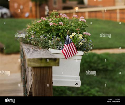 Floral Window Box Holding An American Flag With A Grass Background In