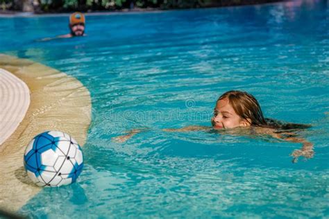 Young Girl Enjoys Swimming In A Pool With A Playful Smile As She
