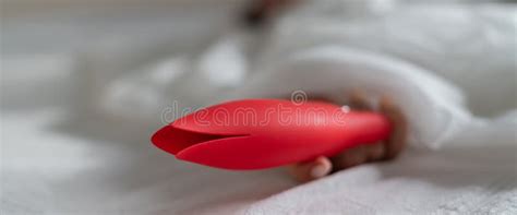 A Faceless Woman Lies In Bed Under A Blanket Holding A Clitoral