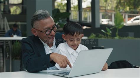 Asian Father Helps Young Son Understand Difficult Exercise During