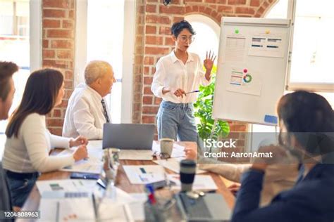 회의에서 함께 일하는 비즈니스 근로자 그룹 그 중 한 명이 사무실에서 동료들에게 프레젠테이션을 하고 있습니다 결정에 대한 스톡