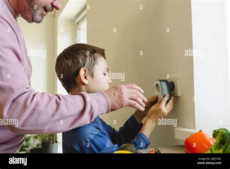 grandfather and grandson installing timer in electrical outlet on wall