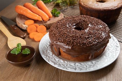 Bolo De Cenoura Brasileiro Com Cobertura De Chocolate Na Mesa De Madeira Com Cenoura Ao Fundo