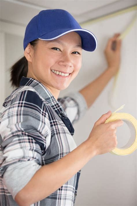 Trabajadora Femenina Que Usa Cinta Para Pintar La Pared Foto De Archivo
