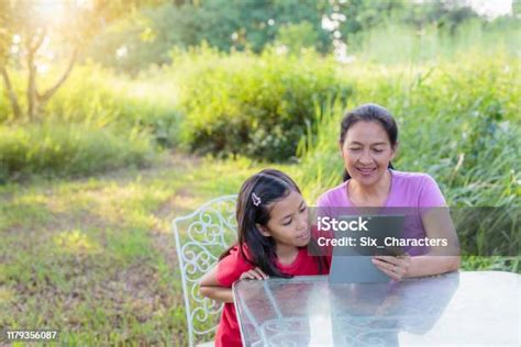 Happy Asian Mother And Her Daughter Using Digital Tablets At Outdoors